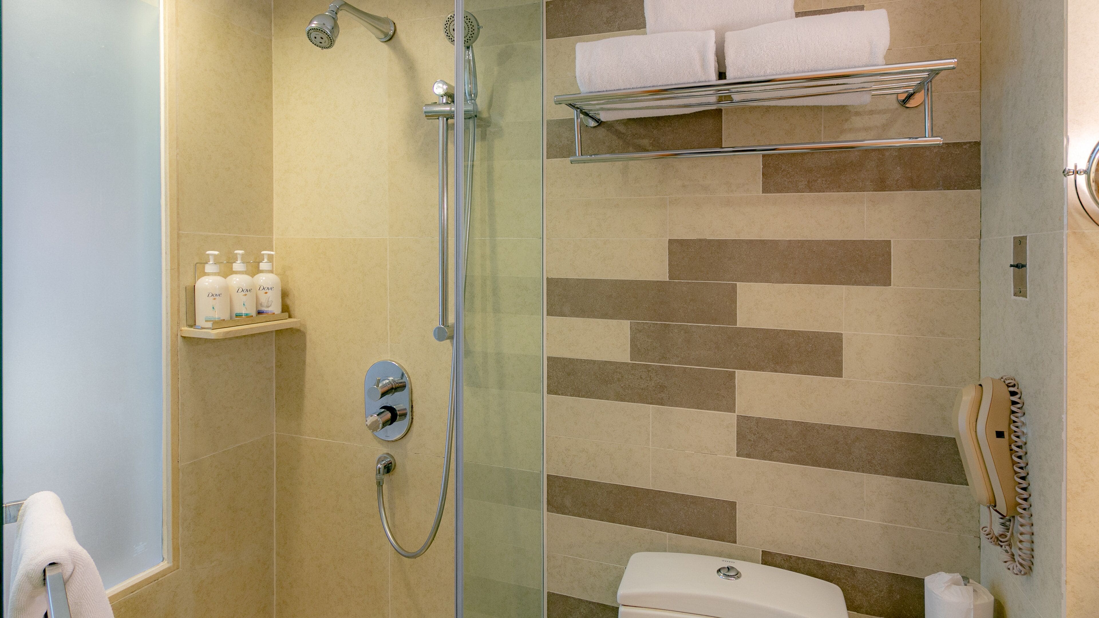 Um banheiro moderno com box de vidro, vaso sanitário e porta-toalhas.