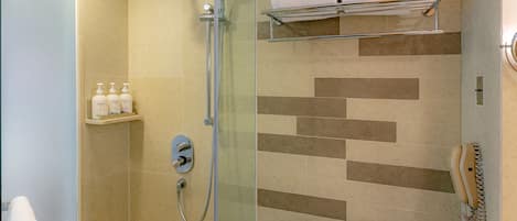 Um banheiro moderno com box de vidro, vaso sanitário e porta-toalhas.