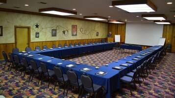 Uma sala de conferência com uma mesa comprida, cadeiras, uma tela de projetor e piso coberto de carpete.