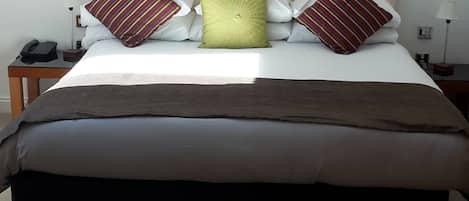 Quarto bem arrumado com uma cama grande, cabeceira de madeira e duas mesas de cabeceira com luminárias.