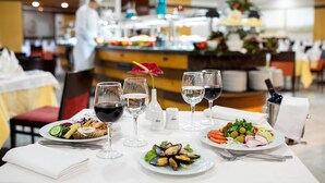Uma mesa de jantar com pratos de comida, copos de vinho e talheres.