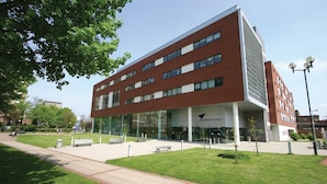 Um edifício moderno com telhado plano, janelas amplas e uma placa com a inscrição 'American Business School'.