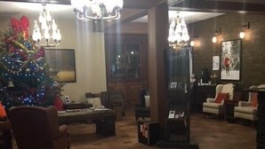 Um hall amplo com uma grande árvore de Natal, assentos confortáveis e um lustre.