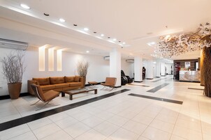 Um lobby moderno com sofá, cadeiras, mesa de centro e balcão de recepção.