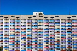 Um edifício com vários andares e fachada uniforme, com varandas em diferentes cores.