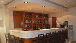 Uma área de bar com balcão e vários banquinhos.