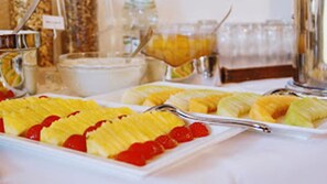 Buffet variado com diversas opções de frutas e um espaço para café.