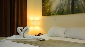 Quarto de hotel com uma cama, uma luminária e um quadro na parede.