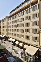 Um hotel com vários andares, varandas, área de estar ao ar livre e espaço comercial no térreo.