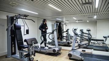 Ginásio com esteiras, máquinas de musculação e um espelho grande.