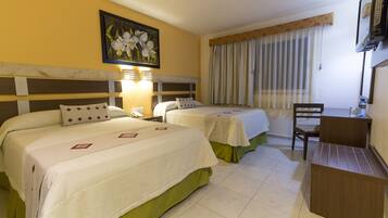 Quarto de hotel com duas camas, uma escrivaninha, uma cadeira, uma televisão e um quadro na parede.
