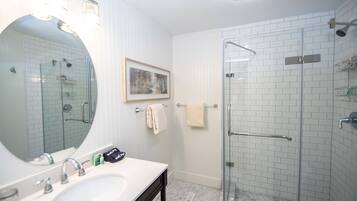 Uma casa de banho moderna com um espelho grande, uma pia e um chuveiro com parede de vidro.