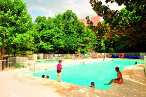 Piscina rodeada por árvores e uma área cercada.