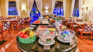 Uma área de buffet com diversos alimentos e uma saladeira de frutas.