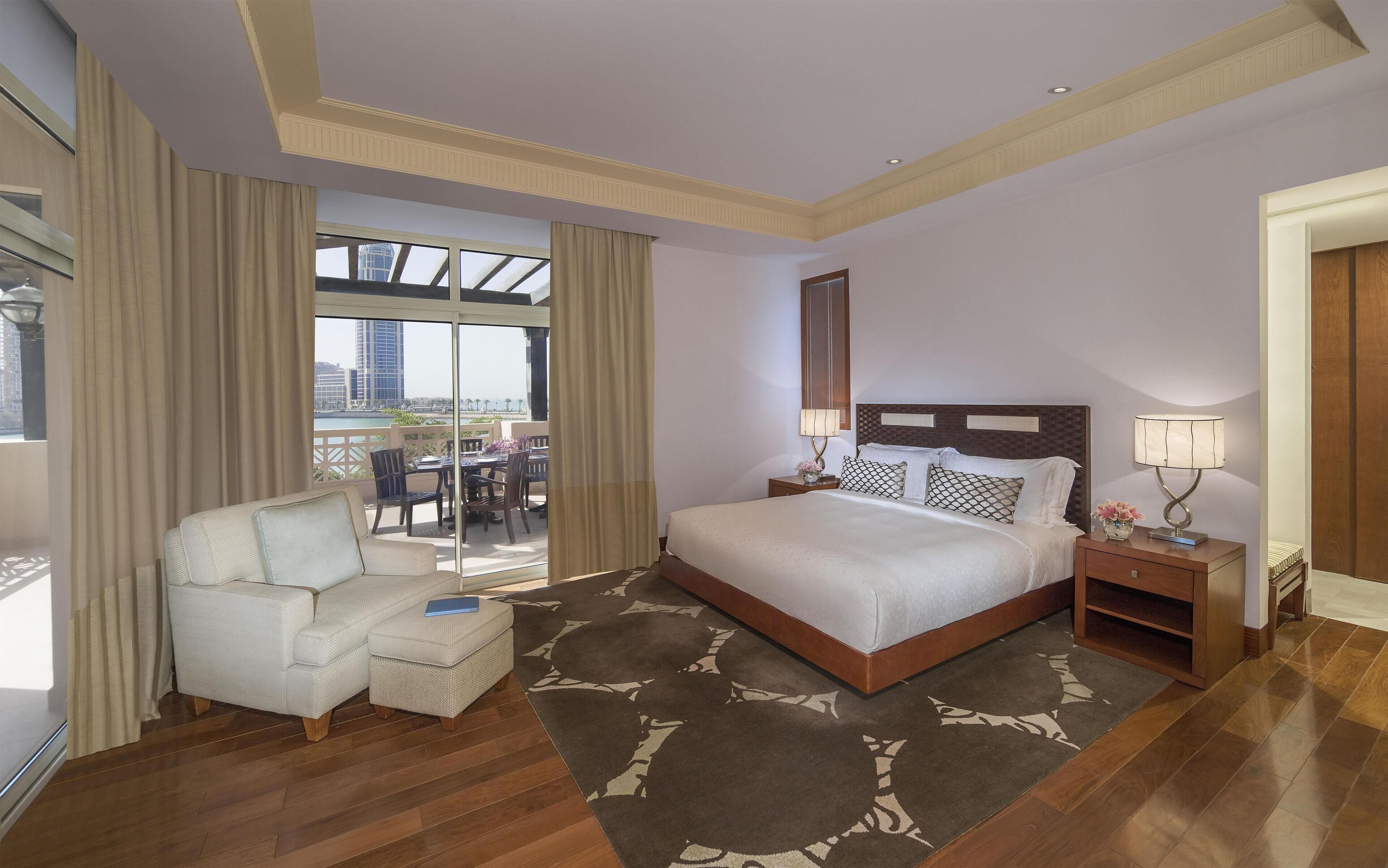 Quarto de hotel com cama, sofá, mesa de jantar e vista da cidade.