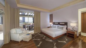 Quarto de hotel com cama, sofá, mesa de jantar e vista da cidade.