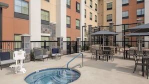 Uma área de piscina com hidromassagem, espreguiçadeiras e guarda-sóis.