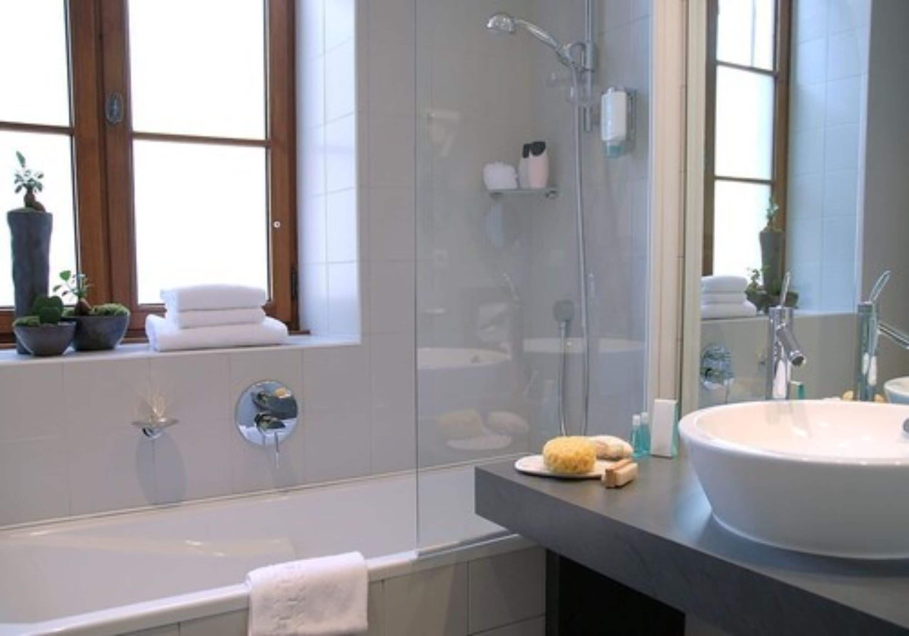 Uma casa de banho moderna com banheira, um espelho grande, uma pia e um chuveiro.