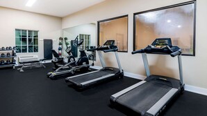 Academia com esteiras, aparelhos de musculação e halteres.