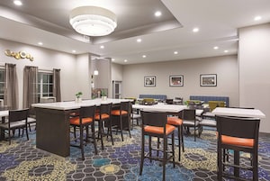 Uma sala de jantar de hotel com várias mesas e cadeiras, um tapete estampado e um lustre no teto.