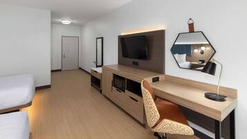 Quarto de hotel moderno com uma cama, uma mesa de escritório com um computador, uma televisão e um espelho.