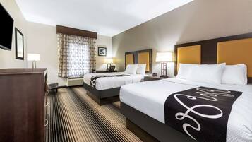 Quarto de hotel com duas camas, televisão de tela plana, escrivaninha e carpete estampado.