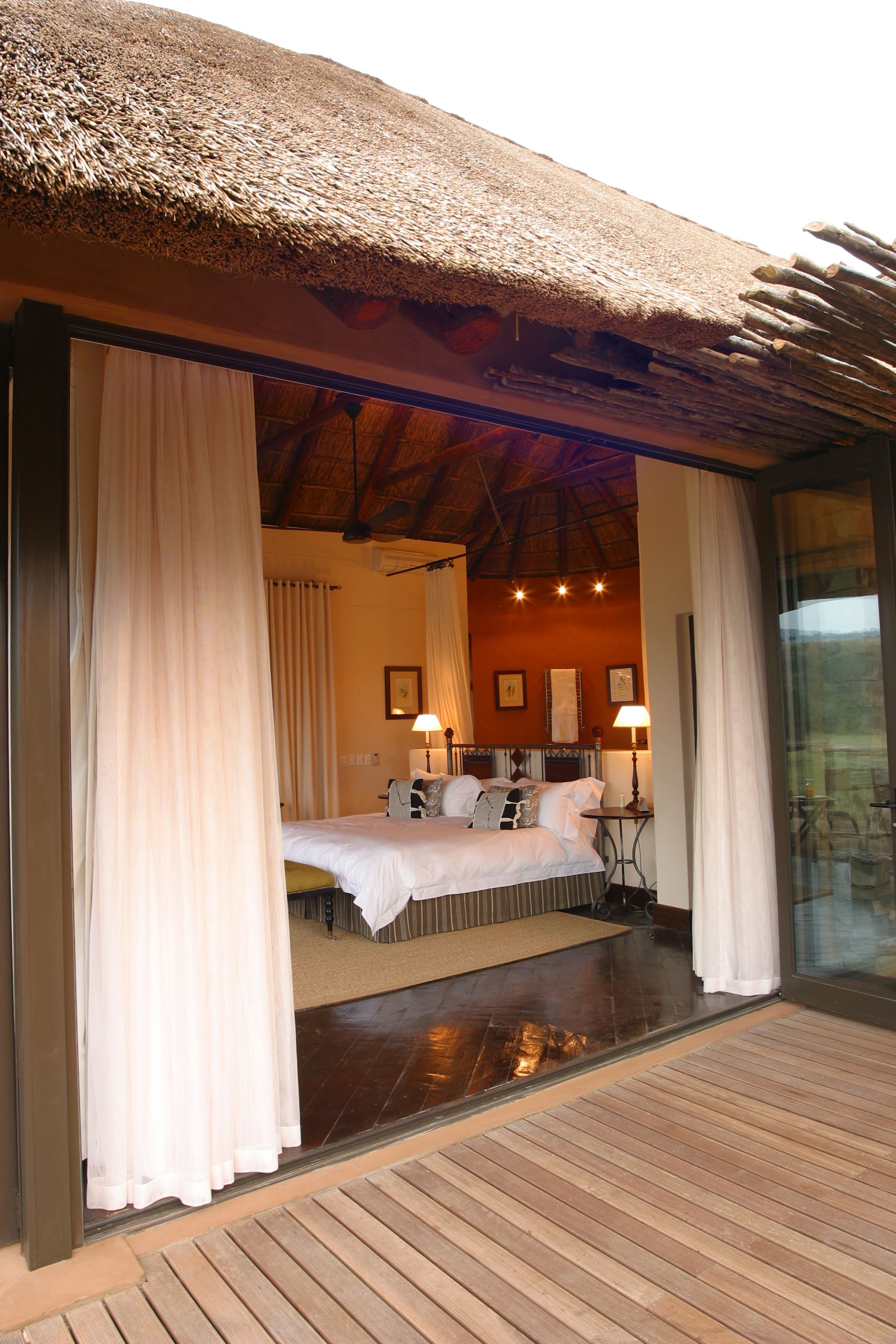 Quarto com uma cama, duas luminárias de cabeceira, uma janela e piso de madeira.
