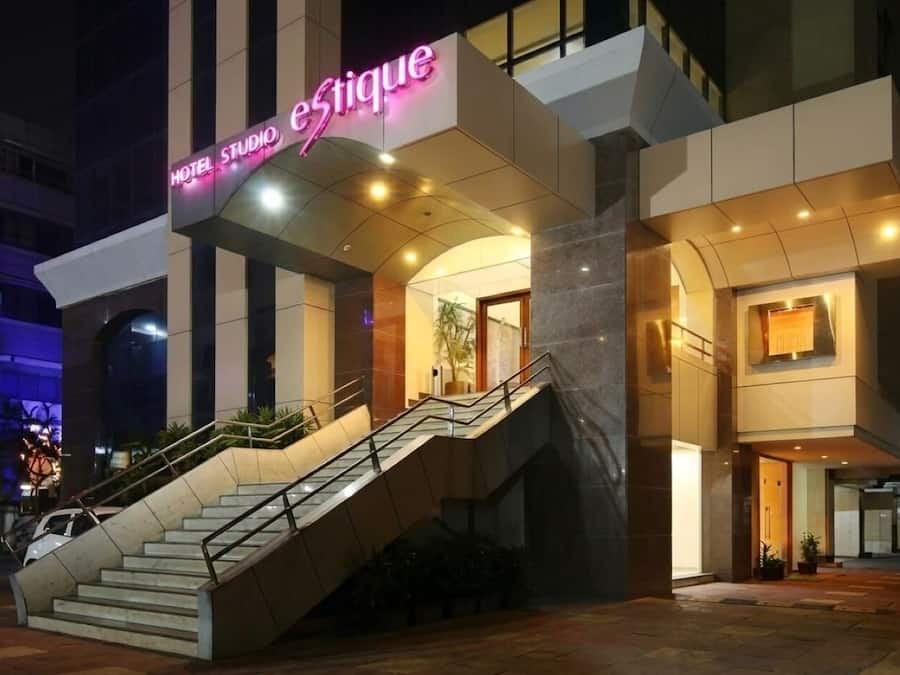 Entrada de hotel com escadaria, letreiro de neon e fachada de edifício moderno.