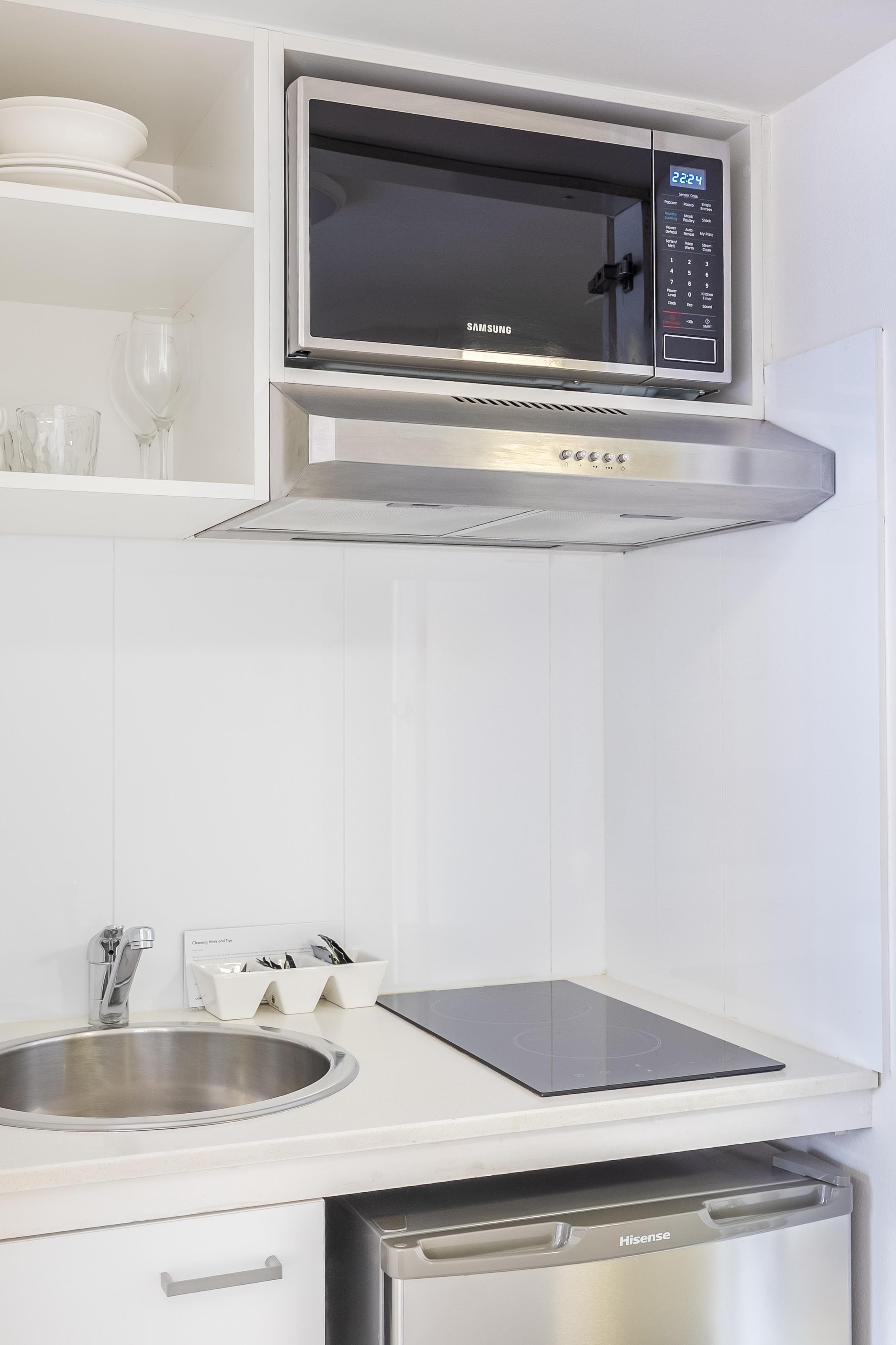 Cozinha moderna com micro-ondas embutido, pia de aço inoxidável e lava-louças.