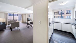Quarto de hotel moderno com área de estar, espaço para refeições e cozinha compacta.