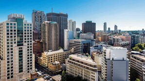 Paisagem urbana com edifícios altos, incluindo um hotel de destaque com design moderno e fachada de vidro extensa.
