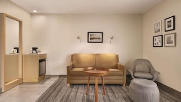 Uma sala de estar moderna com um sofá, um banquinho e uma mesa redonda pequena.