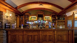 Um bar com vigas de madeira, paredes de pedra e diversas garrafas de bebidas alcoólicas.