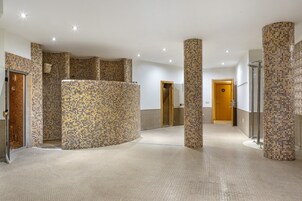 Casa de banho moderna com paredes em mosaico, zona de duche e corredor que dá para uma porta.