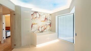 Casa de banho moderna com uma banheira grande, cabine de duche em vidro e teto com um mural floral.
