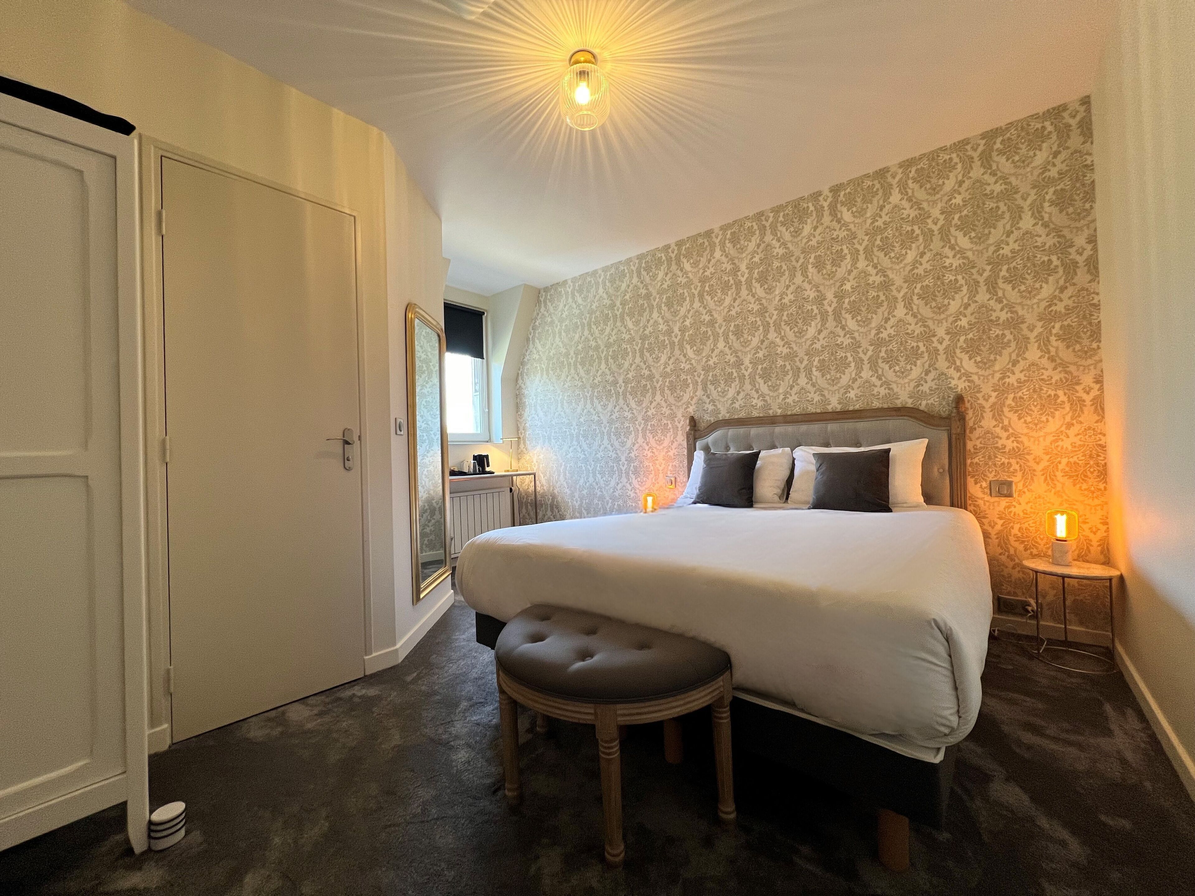 Quarto com uma cama grande, um banco de madeira, um espelho e um radiador.