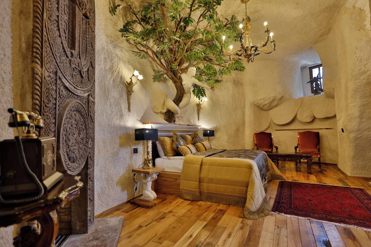 Quarto com uma cama grande, um candelabro e uma escultura de árvore.
