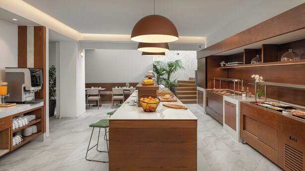 Uma cozinha moderna com ilha central, armários de madeira e uma luminária pendente grande.