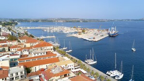 Uma cidade costeira com um porto de iates, edifícios com telhados de terracota e barcos atracados.