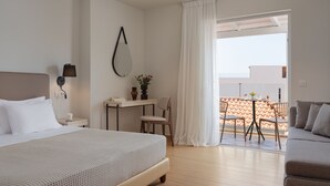 Quarto de hotel com cama, escrivaninha, cadeira e varanda com mesa e cadeiras.