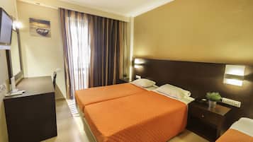 Quarto de hotel com duas camas, uma escrivaninha, televisão e mesa de cabeceira com abajur.