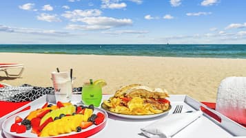 Na praia, areia branca, espreguiçadeiras, guarda-sóis