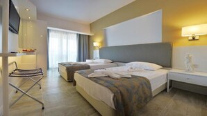 Quarto de hotel com duas camas, uma escrivaninha, uma cadeira e uma televisão.