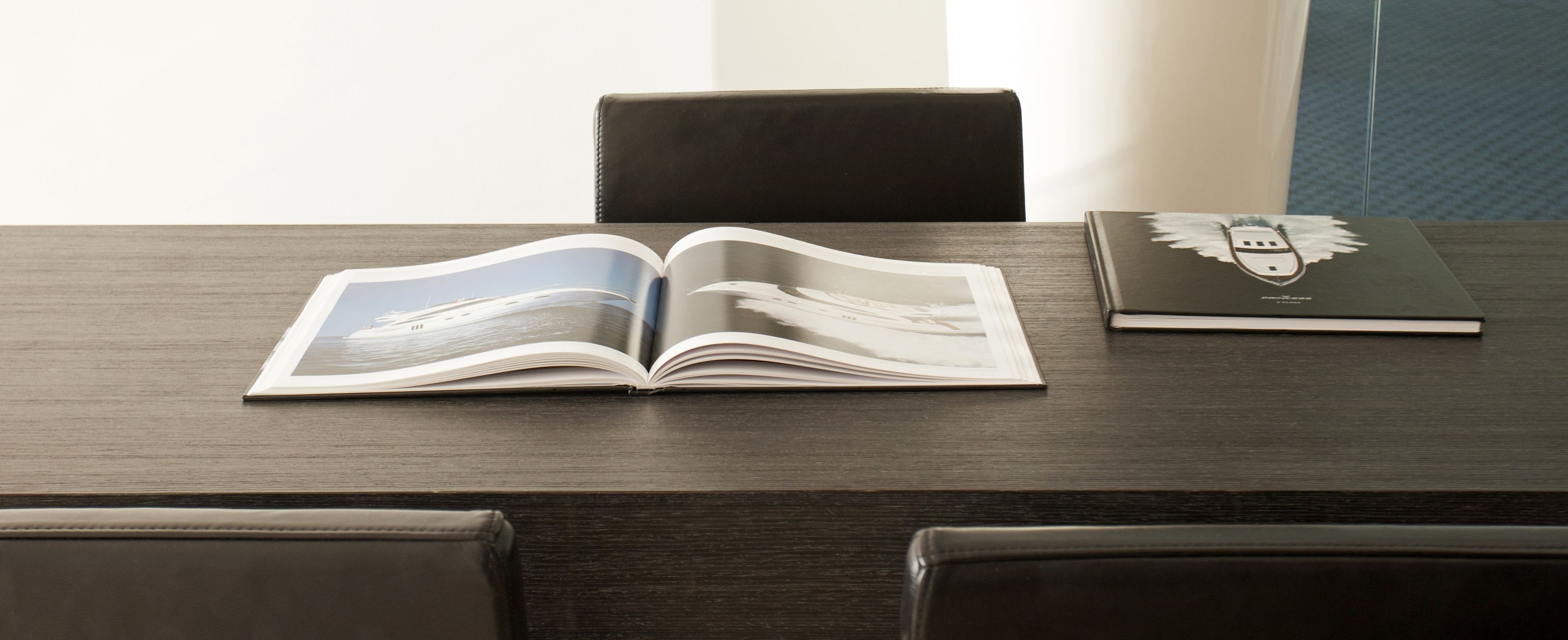 Revista aberta sobre uma mesa de madeira com um livro ao lado.