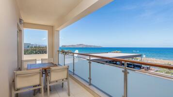 Uma varanda com mesa e cadeiras, com vista para a praia e o oceano.