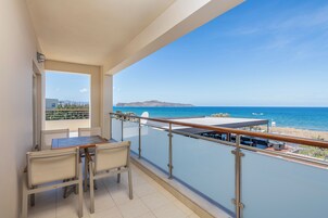 Uma varanda com mesa e cadeiras, com vista para a praia e o oceano.