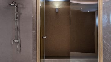 Um chuveiro moderno com porta de vidro, um chuveiro manual e painel de controle fixado na parede.