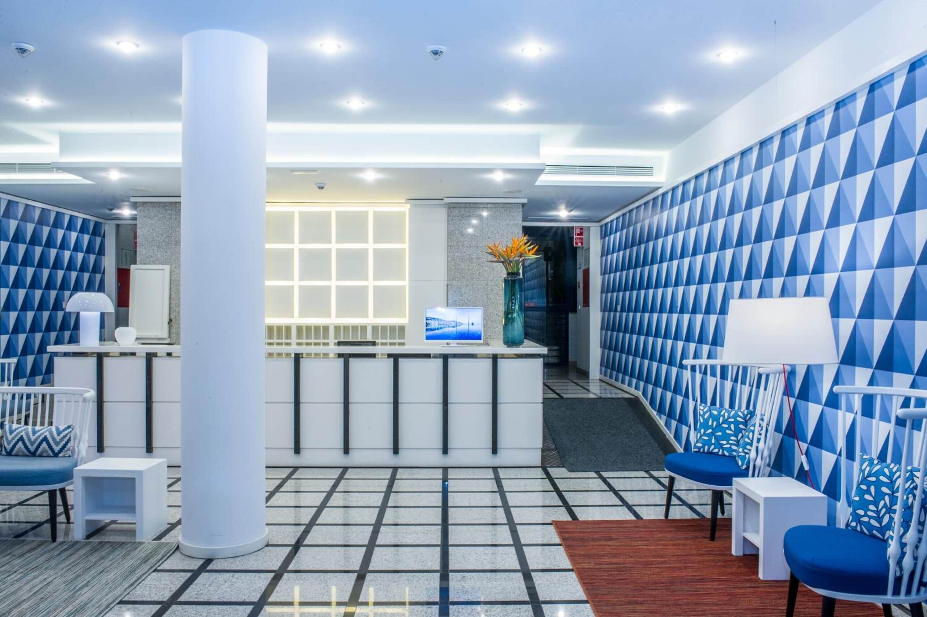Uma área de recepção com design moderno, incluindo um balcão de atendimento, espaço para assentos e elementos decorativos como um vaso com flores.