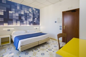 Um quarto com uma cama, mesas de cabeceira, uma porta de madeira e uma cadeira.