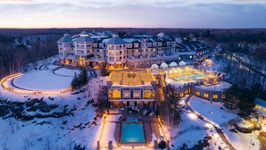 Um grande resort com vários edifícios, piscina e terreno coberto de neve.